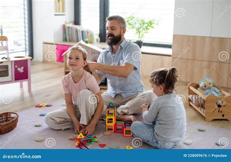 Father With Three Daughters Indoors At Home Playing And Making Hair