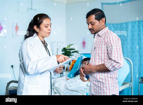 Doctor Explaining Patient Health Or Medical Report To Worried Father At