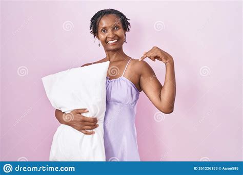 African Woman With Dreadlocks Wearing Pajama Hugging Pillow Looking