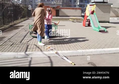 Mom Helps Her Daughter With A Broken Leg To Stand On Crutches In The