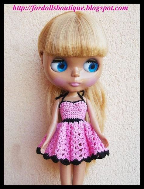 A Doll With Blonde Hair And Blue Eyes Wearing A Pink Crocheted Dress