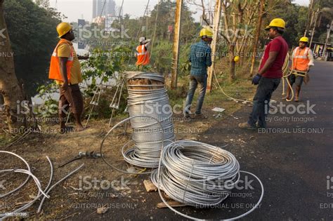foto de dois trabalhadores instalando poste elétrico ao lado da estrada