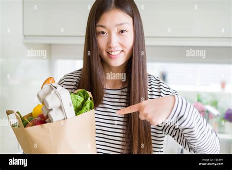 Beautiful Asian Woman Holding Paper Bag Of Fresh Groceries Very Happy