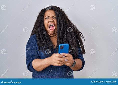 Plus Size Hispanic Woman Using Smartphone Typing Message Angry And Mad