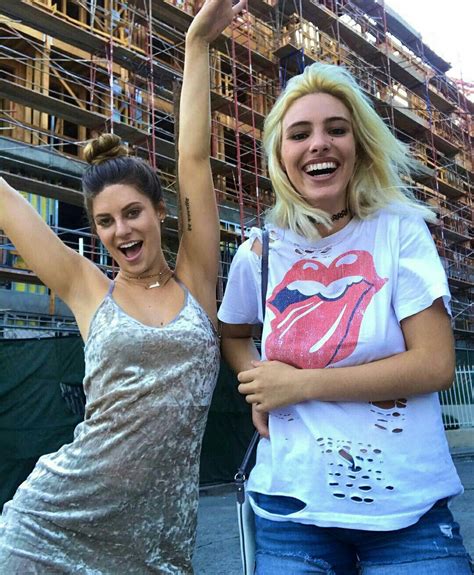 Two Women Standing Next To Each Other With Their Arms In The Air