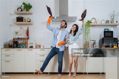 Happy Young Couple Doing Home Chores Singing And Having Fun Funny Woman