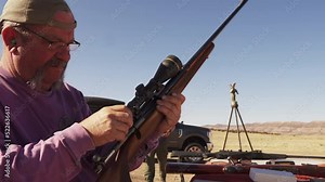 Two Caucasian men at the shooting range setting up R25 rifles, adjusting scope, dolly
