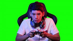 Download Young male gamer intensely playing games on green screen background. for free