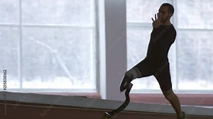 Tracking with slowmo of disabled athlete with prosthetic running leg sprinting on track in indoor stadium