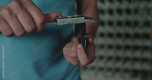 Male hands measuring detail's hole size with calipers on a factory
