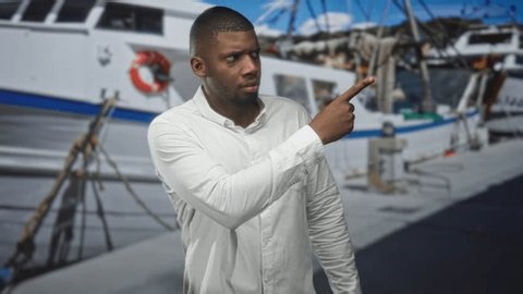 clip-3988714485-man-points-finger-boat-on-dock-studio