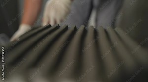 Close-up of a hand running a spatula over a block of mortar. The worker applies the solution to the polystyrene foam with a spatula. The adhesive solution is not worn on the foam block.