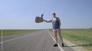 Girl traveler hitchhiking. woman stands on road with cardboard sign in her hand and signals to car on sunny day.