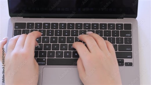Person is typing on a laptop keyboard. The keyboard has a number pad and a shift key
