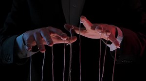 Puppet Master Controls and Manipulates Marionettes with Strings Attached To His Fingers