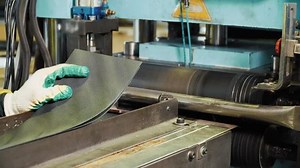 La production du geogrid dans la machine à transporter à l'usine. Un ouvrier met les mains dans les gants et met un produit dans la machine. Gros plan.