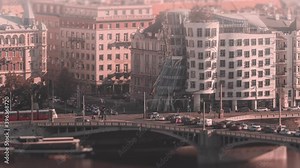The crossroad in front of the famous Dancing House in Prague. Traffic is slow, there is no usual traffic jam. Trams, cars, and lorries moving on the street. The thin orange haze hanging in the air.