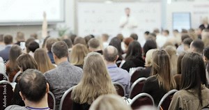 Seminar, meeting, training, conference in group. Public speech concept. Educational finance lectures for startuppers. Business training with man speaker talking in large audience, view from viewers.