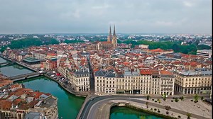 Aerial view of Bayonne city in Basque Country region by the river. Narrow medieval streets and red rooftop buildings. Twin towers rise from hilltop Gothic cathedral with medieval cloisters in France.
