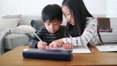 Japanese schoolboy getting help from his young sister as they do...