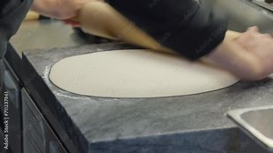 Close Up Of Making Pizza Dough Using Rolling Pin And Adding Flour. Rolling Pin Stretching Dough For Italian Cuisine Pizza Cooking. Pizza Dough Raw Ingredient. Rolling Pin Food Preparation Utensil