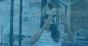 Using virtual reality headset, woman interacting with data visualization animation over office backg