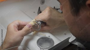 Worker is operating the cutting device to create prosthetic teeth. Cutting the prosthetic teeth with a specialised dental device. Cutting out a part of prosthetic teeth with a stomatology device.