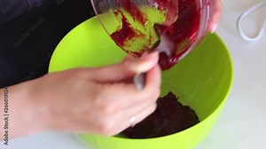 A woman shifts cranberry puree from one container to another. For the preparation of marshmallow.