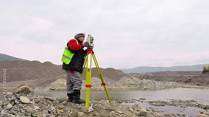 Surveyor is using newest geological equipment to analyze area. Surveyor is operating the geological theodolite equipment with moveable telescope. Surveyor measuring quarry using geological equipment