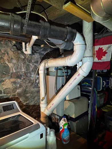 The image shows a cluttered basement with exposed pipes and a washing machine. | Plumbing Only