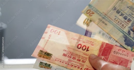 Woman counting hong kong dollar banknotes, demonstrating finance transaction, wealth, and bank savings concept.