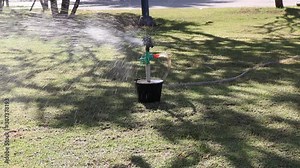 Lawn water sprinkler on green grass meadow field spraying and watering water splash at outdoor garden in summer seasonal.