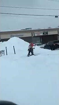 Woman Strolls in Street in Skis Carrying a Baby in a Back Carrier - 1097616