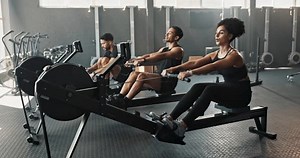 People, rowing machine and gym workout for cardio exercise or fitness teamwork, friends or challenge. Men, woman and healthy training at sports centre together or athlete goals, wellness or endurance