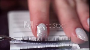 Volume eyelash extensions done. Lash master putting a strip of false eyelashes on the palette with eyelash tweezers. recording in real time.