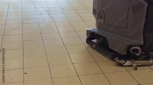 Morning maintenance highlights glossy tiled flooring. Cleaning crew enhances mall entrance appearance before opening hours