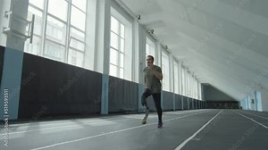 Slow motion shot of professional sportsman with prosthetic leg running on track while exercising at indoor stadium