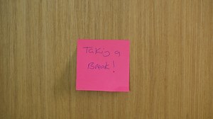 Hand seen placing a post it note on a door that says "taking a break!" - pink paper note displays break message | Premium Stock Video Footage