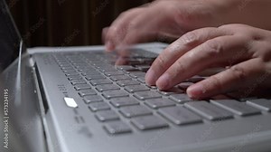 Close up select focus of woman hands typing on a laptop computer keyboard, Woman speed working with thai language keyboard at night in Thailand.
