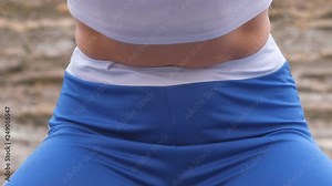 Flat belly girl during diaphragmatic breathing exercises bodyflex on the rock background. Belly close-up view.