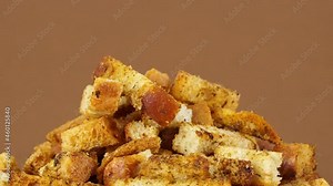 Crispy bread cubes, extremely macro view, crouton or brown roasted tostes rotating on brown. Crouton or roasted crackers cubes rotating in wooden plate. Mock up image of homemade croutons in a bowl. Stock Video
