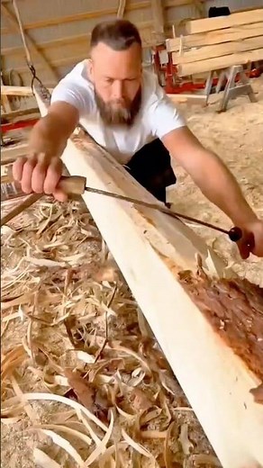 Shaving bark and smoothing the wooden beam surface using a traditional drawknife tool