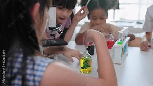 Elementary pupil grouping experiment drop substrate in test tube or beaker in science subject in classroom. Teacher female explains about chemical reactions to children at kindergarten school.