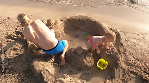 Father and daughter building sand castle at the beach