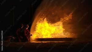 Fireman or firefighter from fire department wearing fire protection suit and helmet and breathing with oxygen tank hold the water hoses extinguish the fire from the gas pipe and valves