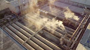 Footage 4K over the Chemical plant cooling tower smoke equipment. The drone fly over the industrial roofs and cooling tower equipment with smoke exhaust in chemical plants.