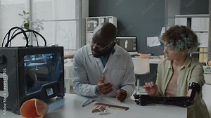 African American prosthetist explaining how prosthetics 3D printing works to young girl with disability during consultation in clinic