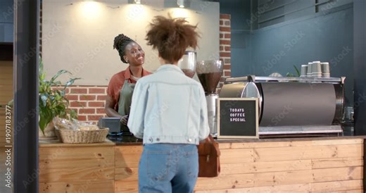 African American women at counter, customer approaching, reaching bag, ordering, barista using POS