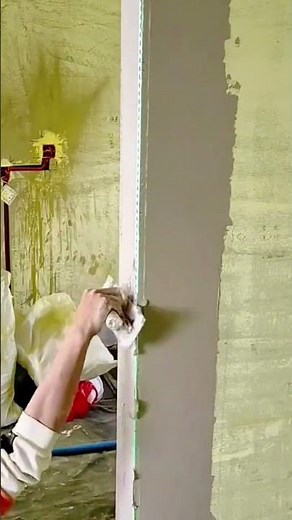 Worker leveling wall plaster using laser guide for precision alignment