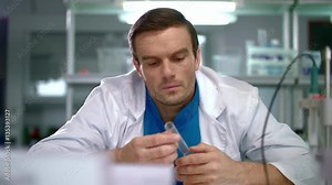 Researcher checking flask. Researcher blowing in glass flask. Researcher working. Male scientist work with laboratory glassware. Laboratory worker checking laboratory equipment